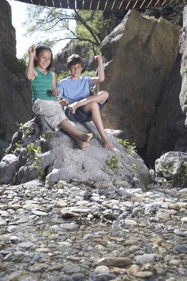 Boy and Girl (10-12) Sitting on Rock Throwing Stones Stock Photo ...