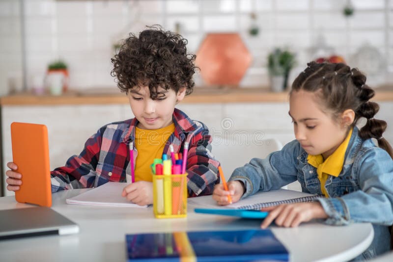 Boy and Girl Sitting at Round Table, Holding Tablets, Making Notes ...