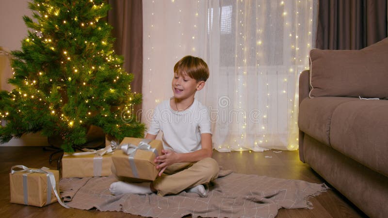 The Boy Goes To Open Christmas Gifts Under the Christmas Tree Stock ...