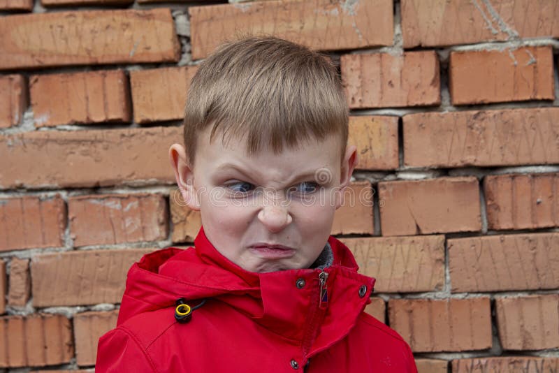 The Boy is Grimacing in Anger. Angry Face of a Boy in a Red Jacke Stock ...