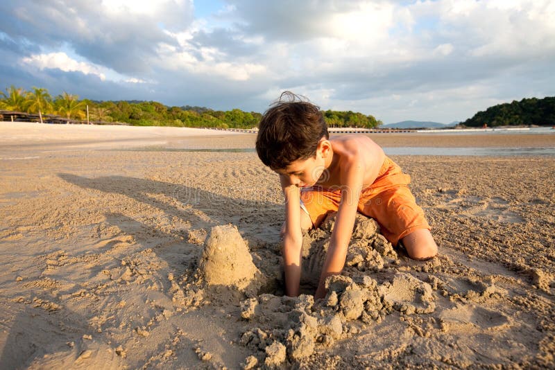 Boy Having Fun Outdoors Playing in the Sand by the Beach at Sunset ...