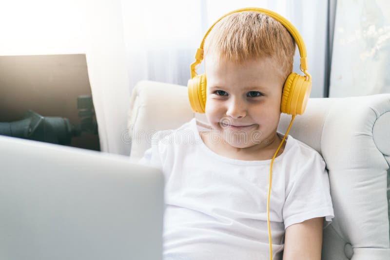 A Boy in Headphones Looks at a Laptop Screen. Stock Photo - Image of ...