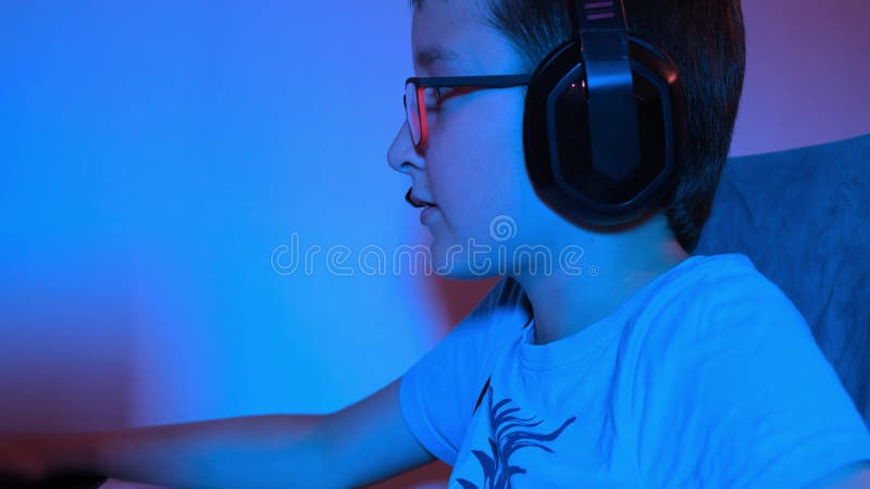 A Boy in Headphones Playing Online Computer Game at Night, he is ...