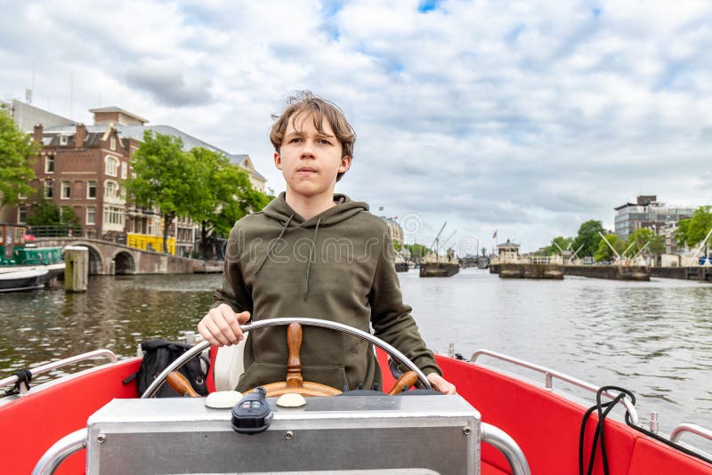 A Boy at the Wheel of a Boat on a Canal in Amsterdam Stock Image ...