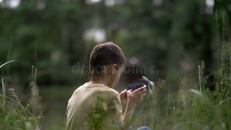 Boy Hiding and Playing in the Phone Outoors, Back View Stock Photo ...