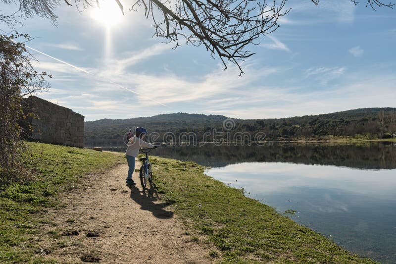 A Boy with His Bicycle on a Path Next To a Lake Stock Photo - Image of ...