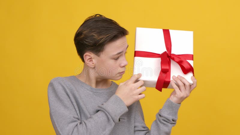 Boy Holding and Shaking Wrapped Gift Box Posing, Yellow Background ...