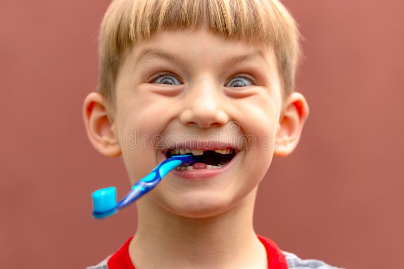 The Boy Holds the Toothbrush in His Teeth with the Reverse Side Stock ...
