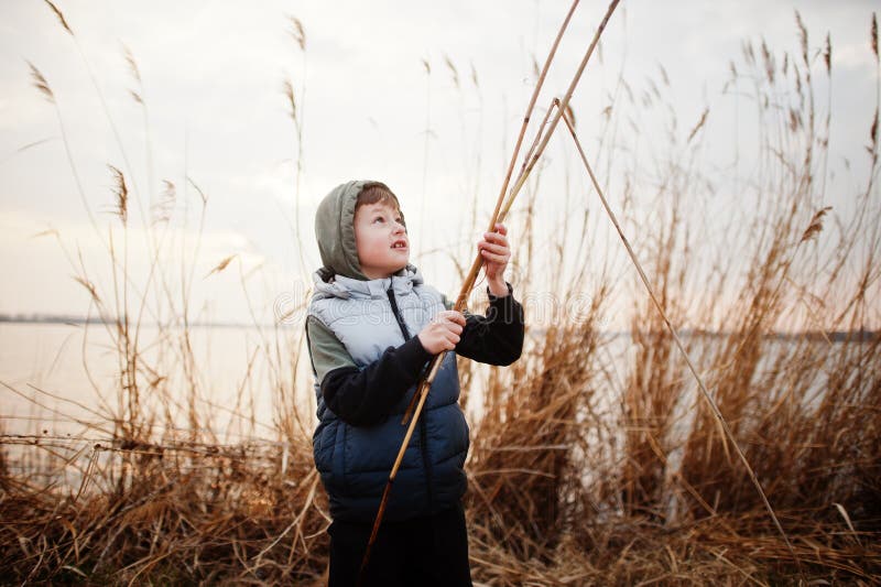 Boy in Hoodie by the Lake with a Reed in His Hands Stock Photo - Image ...