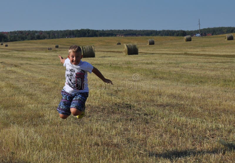 Boy Jumping in Near Haystacks Stock Photo - Image of rainbow, meadow ...