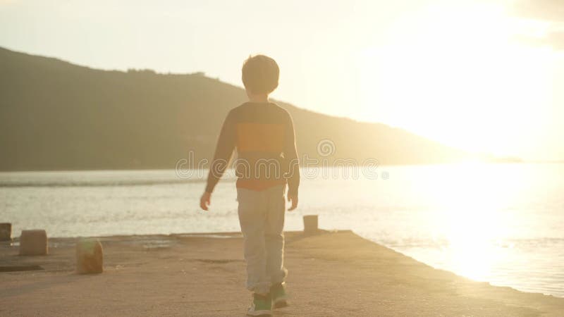Boy Jumping on the Pier on the Seashore Against the Backdrop of Sunset ...