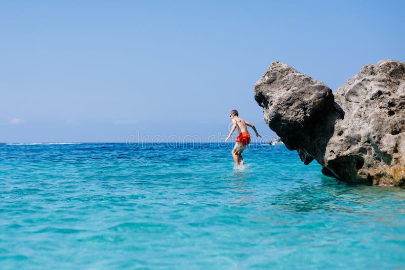 The Boy is Jumping from the Rock into the Water Stock Photo - Image of ...