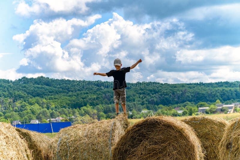 Boy Jumping on Round Straw Bales Stock Image - Image of hands, person ...