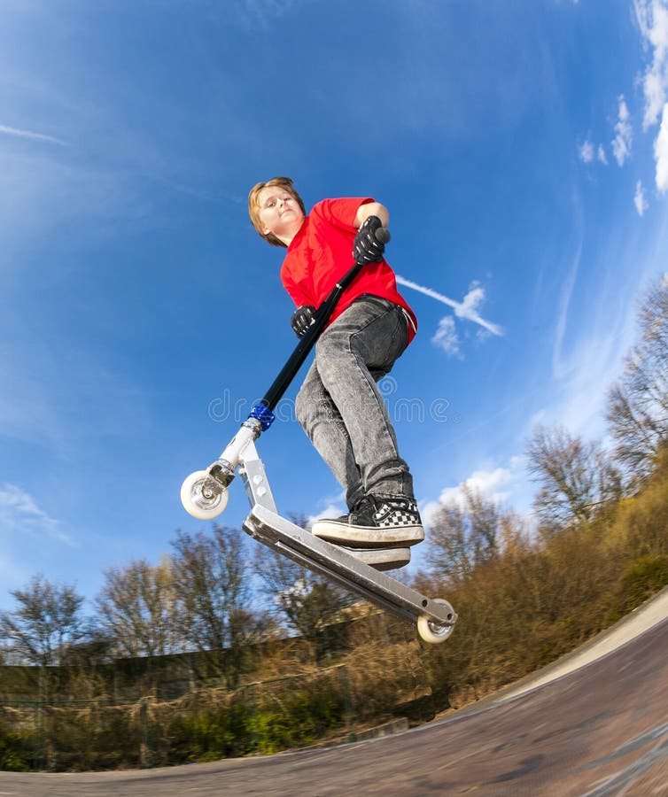 Boy is Jumping with a Scooter Over a Spine in the Skate Park Stock ...