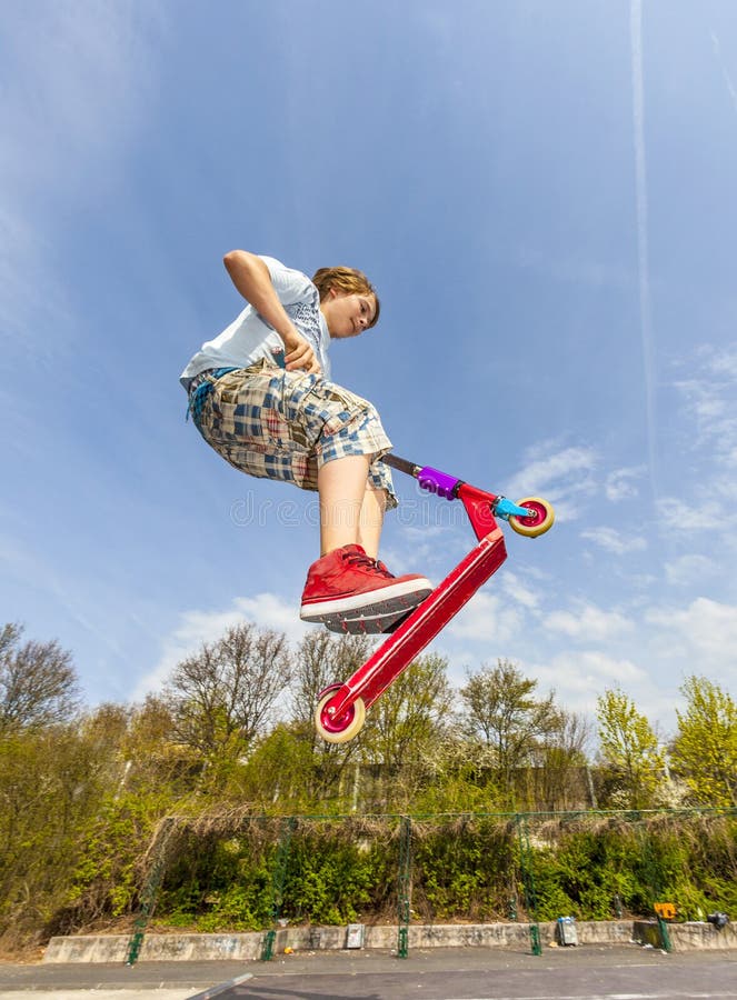 Boy is Jumping with a Scooter Over a Spine in the Skate Park Stock ...