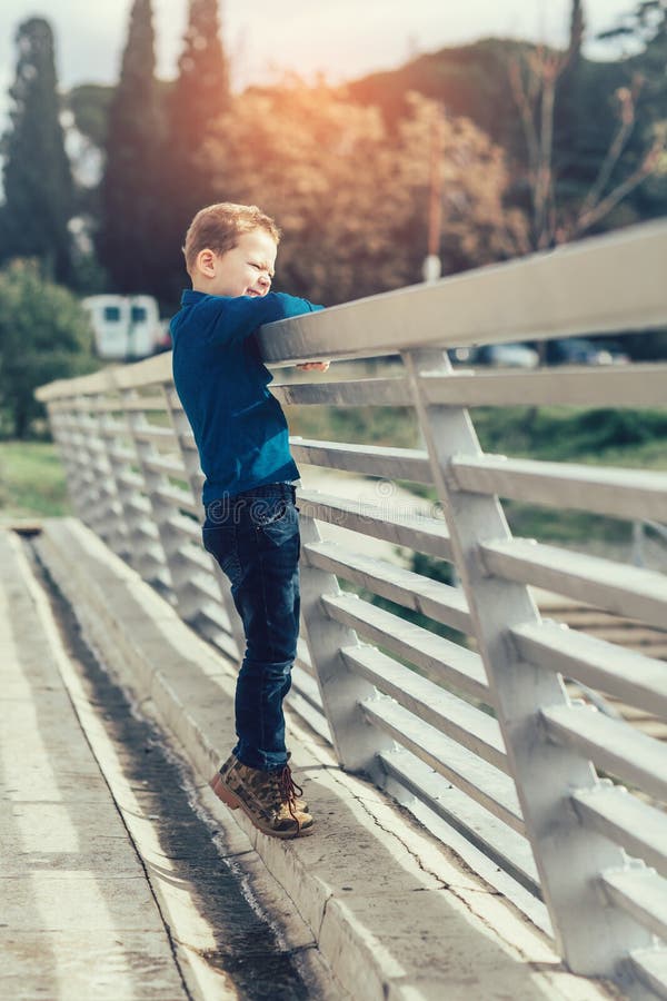 Boy Leaning Over a Bridge Railing Looking Down at River Stock Image ...