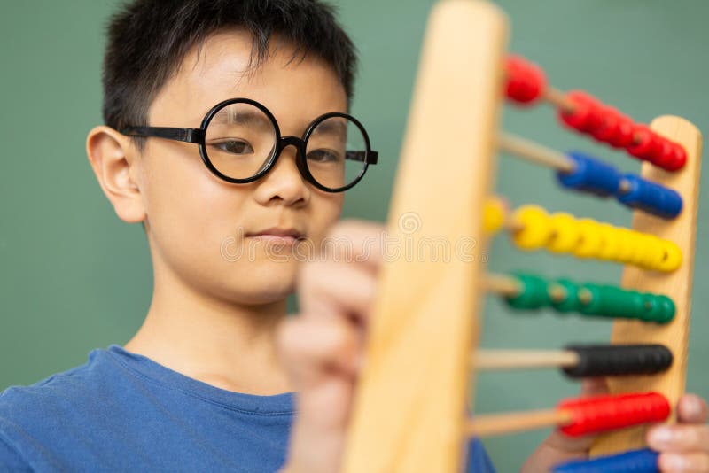 Boy Learning Math with Abacus Against Green Chalkboard in a Classroom ...