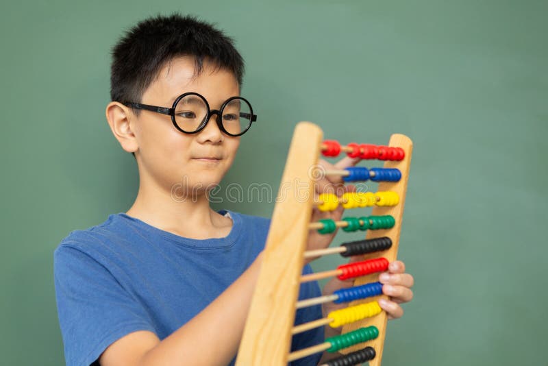 Boy Learning Math with Abacus Against Green Chalkboard in a Classroom ...