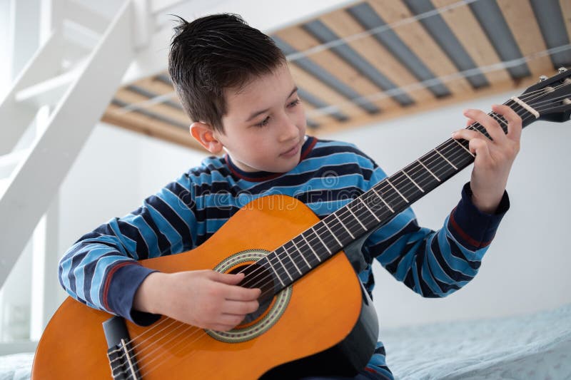 Boy Learning To Play Acoustic Guitar. Boy is Practicing Acoustic Guitar ...
