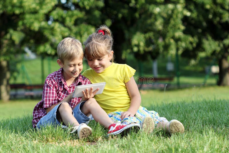 Boy and Little Girl Play with Tablet in Park Stock Image - Image of ...