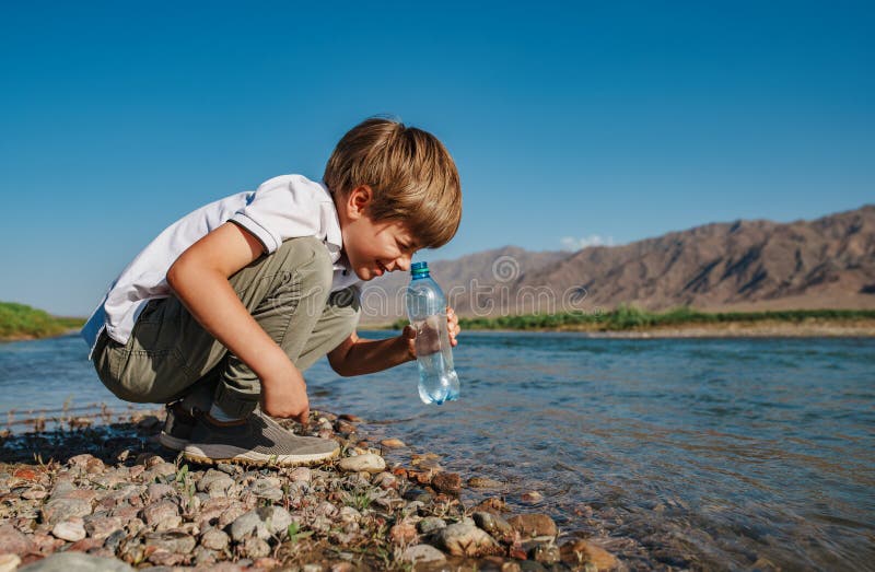 Boy Looking into the Bottle of Water Drawn from a Mountain River Stock ...