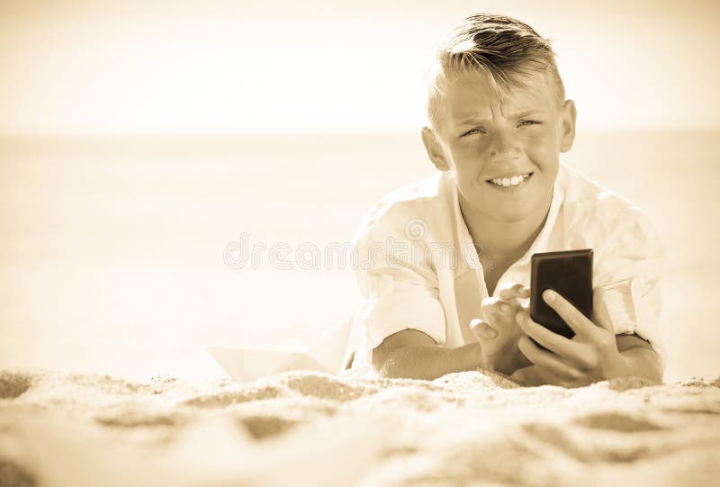 Boy Looking at Phone while Resting on Beach Stock Photo - Image of ...