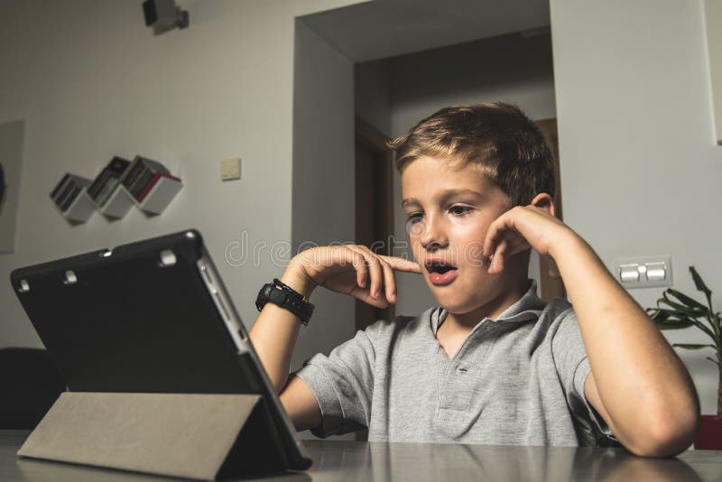 Boy Looking Surprised Looking at a Tablet at Home. Child Looking at a ...