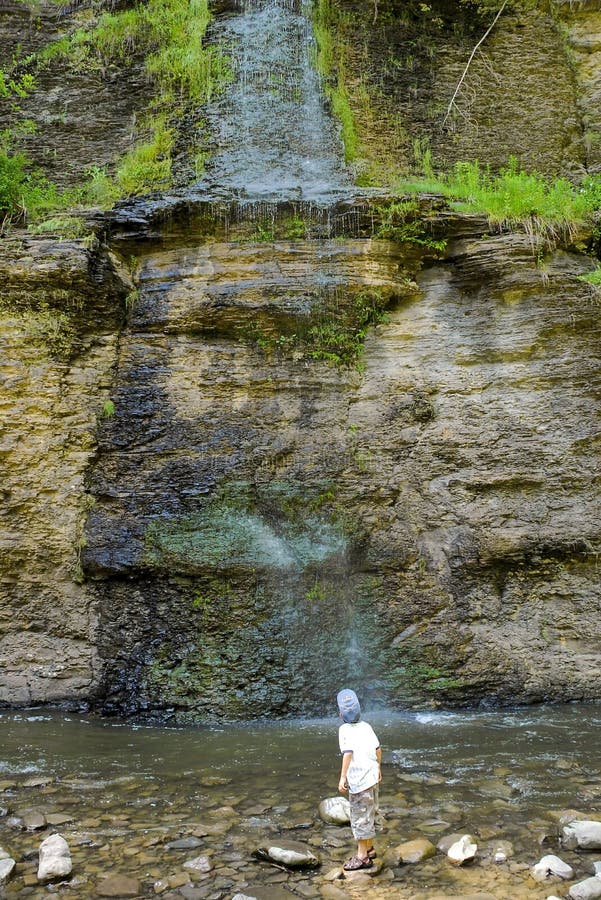 Boy Looking Up at Cliffs Trickling Waterfall Stock Image - Image of ...