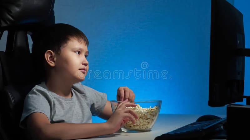 Boy Looks at the Computer Funny Video and Eats Popcorn Stock Photo ...