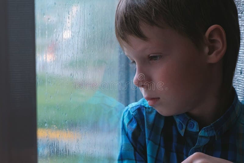 Boy Looks Out the Window in the Rain and is Sad. Stock Image - Image of ...