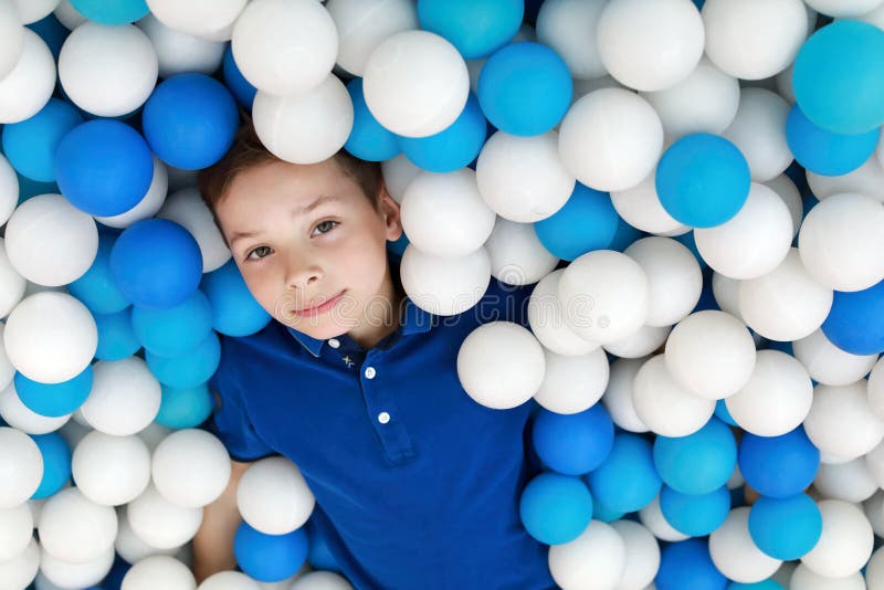 Boy lying in ball pit stock photo. Image of activity - 156381634