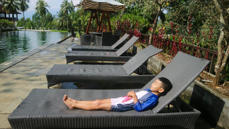 A Boy Lying on a Chair by the Pool Stock Photo - Image of little, beach ...