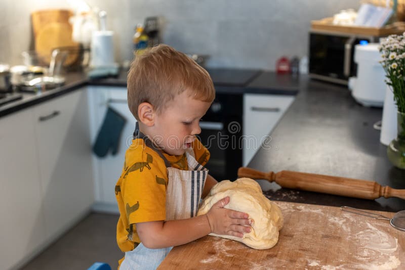Boy Making a Cake. Kid in an Apron in the Kitchen Kneads Dough with Her ...