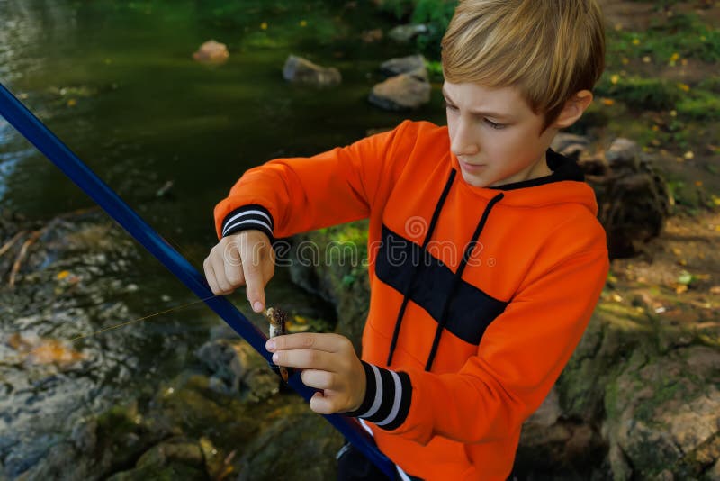 A Boy in Nature Near the River is Removed the Hook of a Caught Fish ...
