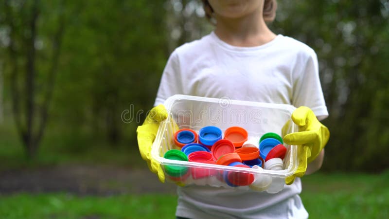 A Boy in the Park Holds Plastic Colored Lids in a Plastic Container ...