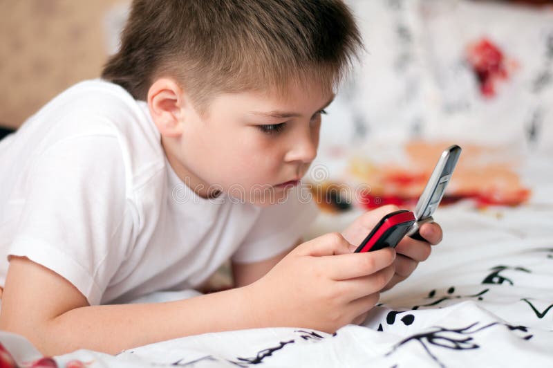 Boy playing on cell phones stock photo. Image of lying - 27686214