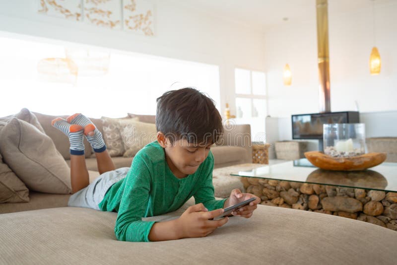 Boy Playing Game on Mobile Phone while Lying on Sofa at Home Stock ...
