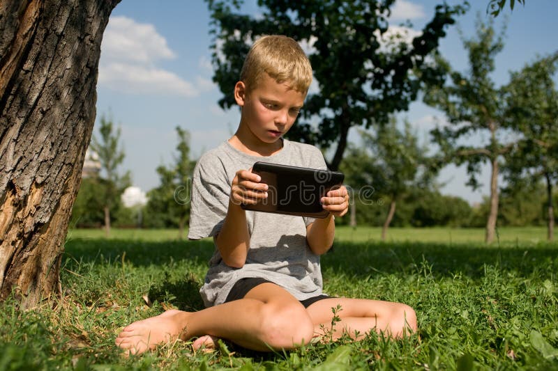 Boy Playing in the Tablet PC Stock Photo - Image of black, outdoors ...