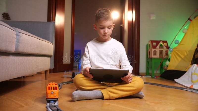 Boy Playing with Toy Railroad, Starting the Train Using a Tablet Stock ...