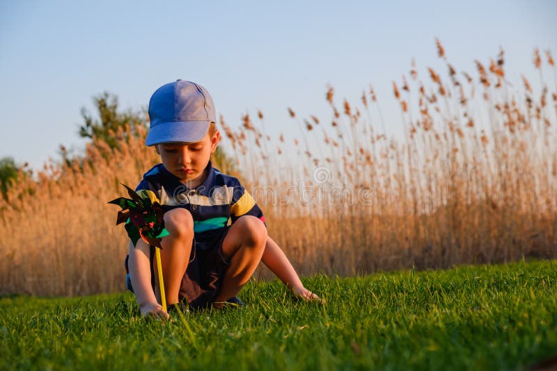Boy Playing with Windmill in Green Grass of the Beach on Summer ...