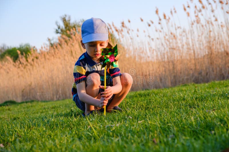 Boy Playing with Windmill in Green Grass of the Beach on Summer ...