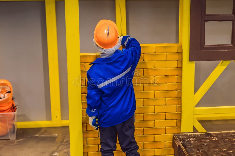 A Boy Plays in the Builder in Construction Clothes and a Helmet Stock ...