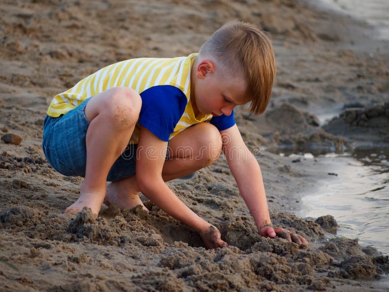 Boy Plays with Sand on the Beach Near the Water Stock Photo - Image of ...