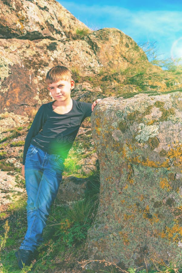 A Boy Poses for a Photo Shoot, Leaning on a Large Rock on the Rocks ...