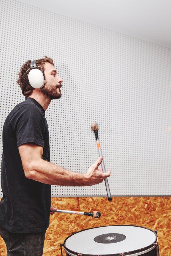 A Boy in Profile Holding a Mace with a Drum in Front and Ear Protection ...