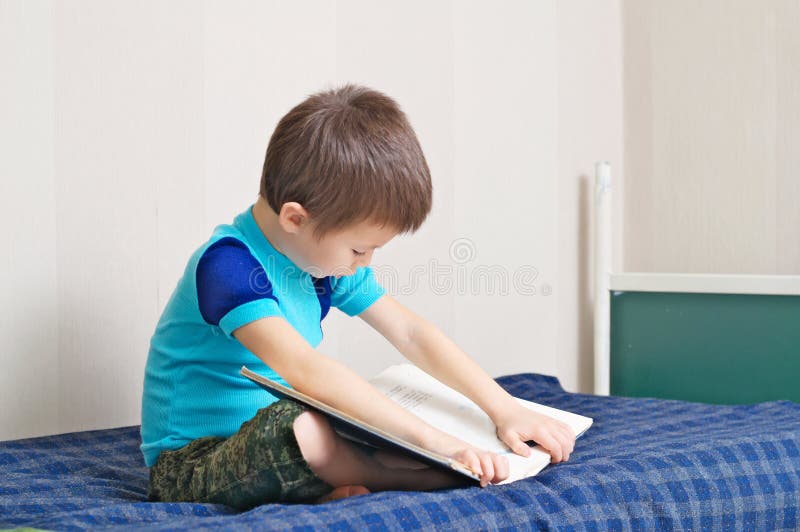 Boy reading book on bed stock image. Image of indoor - 80116669