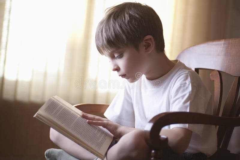 Boy Reading Book on Chair at Home Stock Photo - Image of student ...