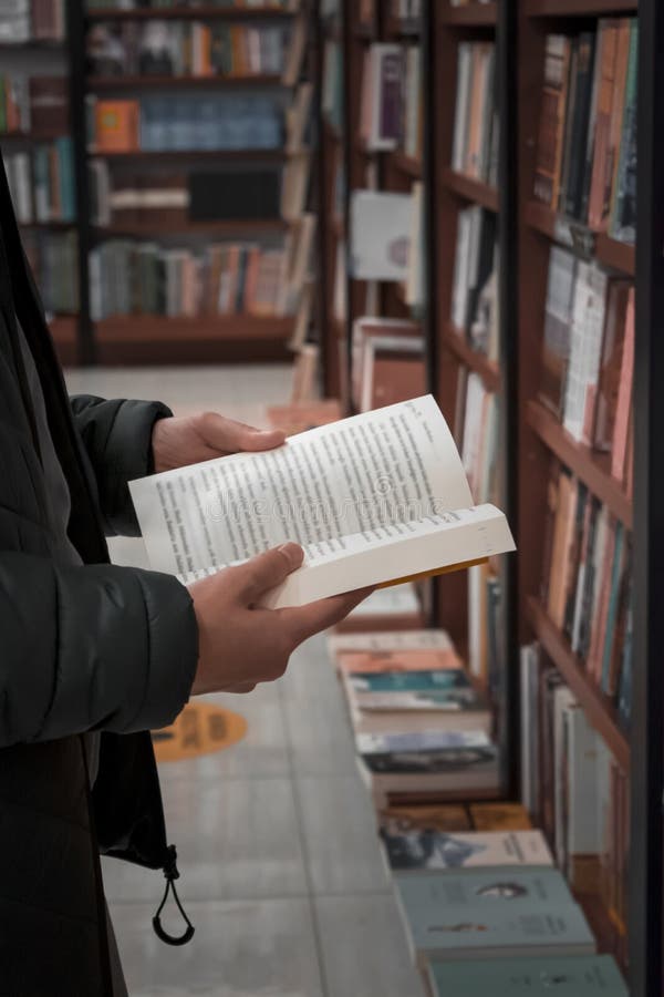 Boy Reading a Book in Front of Shelves in a Bookstore Stock Photo ...