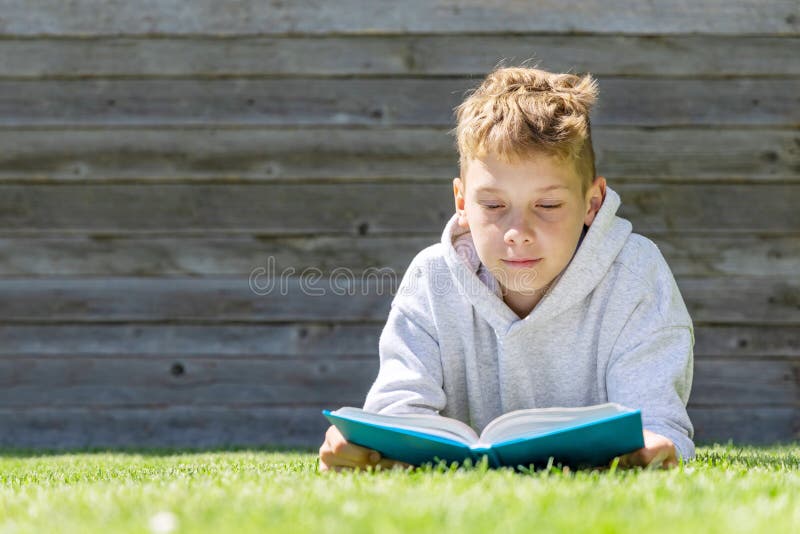 A Boy Reading a Book on a Grass Stock Image - Image of outdoors ...