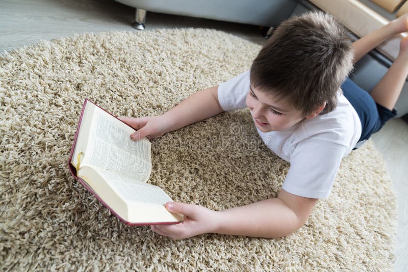 Boy Reading a Book while Lying on Carpet in the Room Stock Image ...
